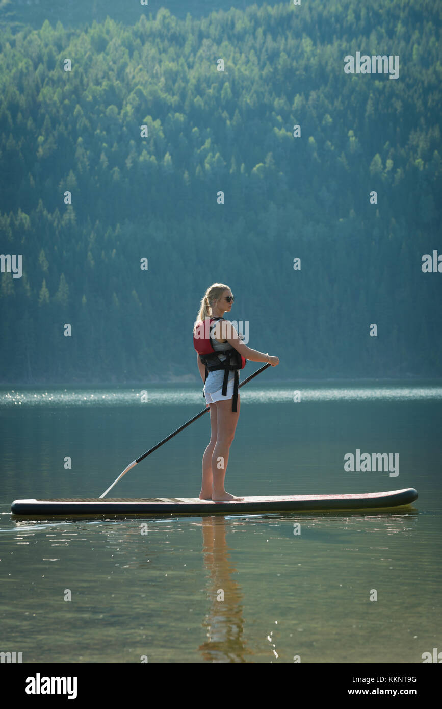 Woman doing stand up paddleboarding in river Stock Photo - Alamy
