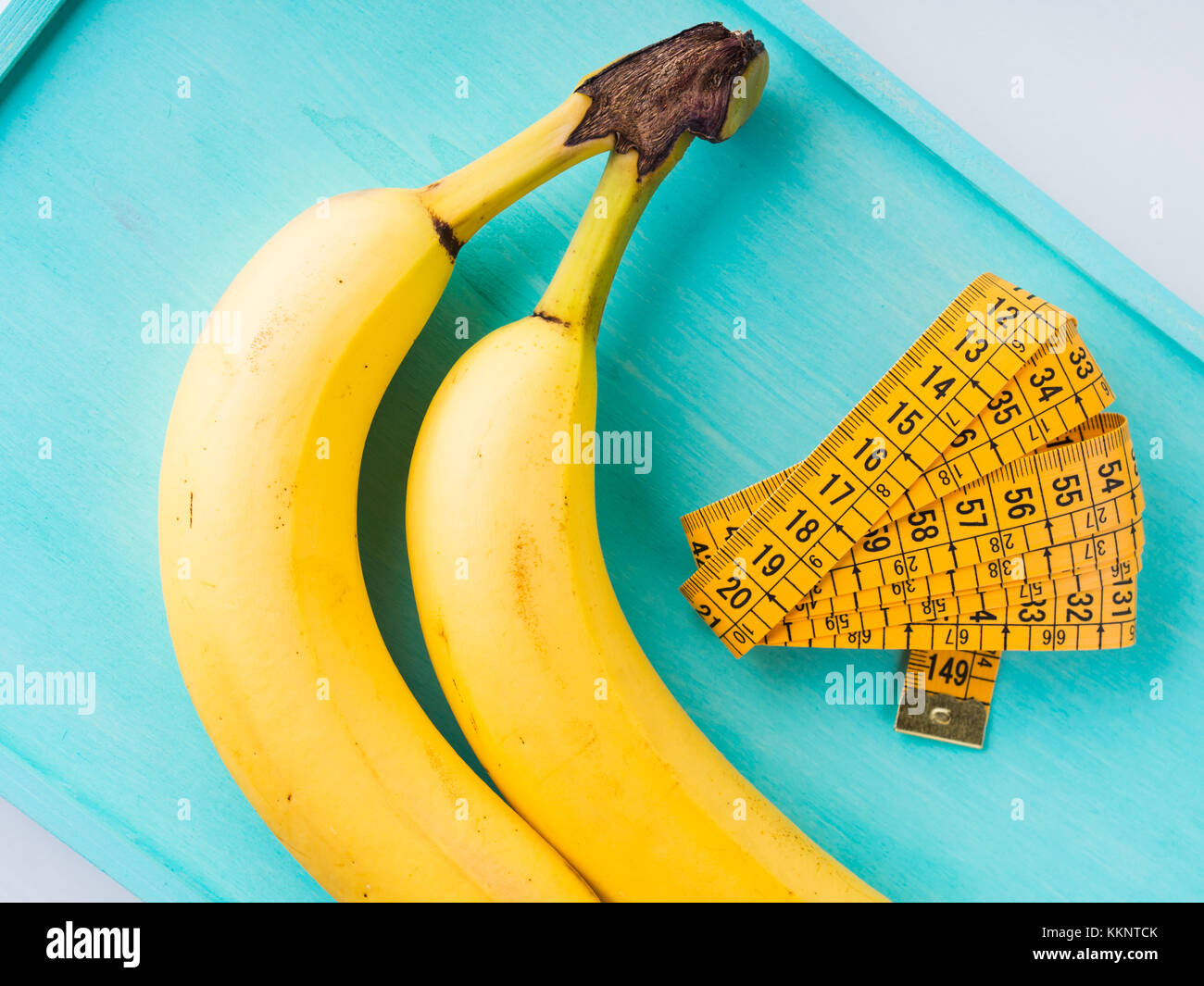 Two bananas with measuring meter on green pastel Stock Photo - Alamy
