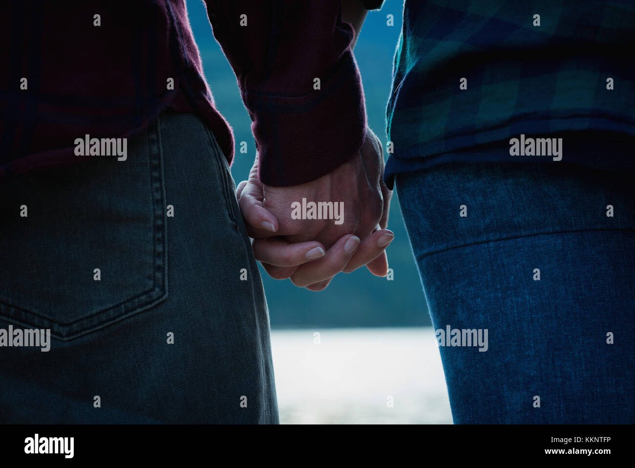 Couple holding hands near riverside Stock Photo - Alamy