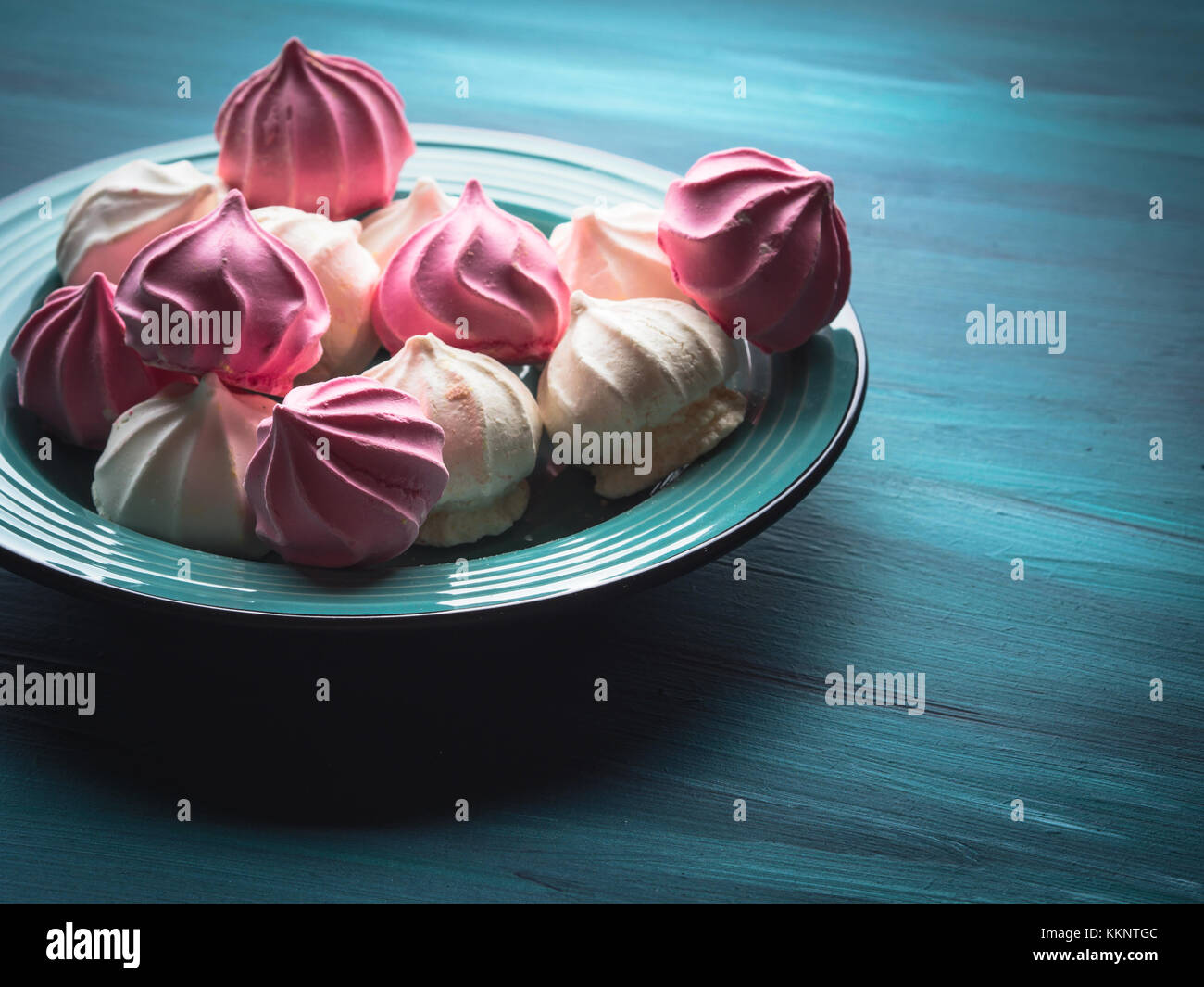 Pastel color pink and white meringue on green background Stock Photo ...