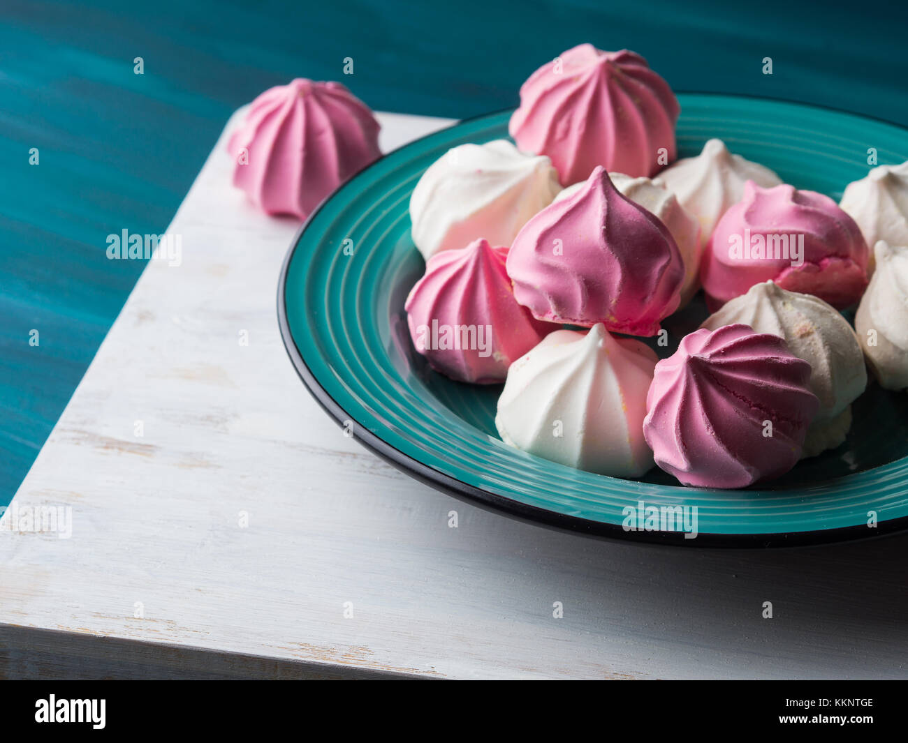 Pastel color pink and white meringue on green background Stock Photo ...