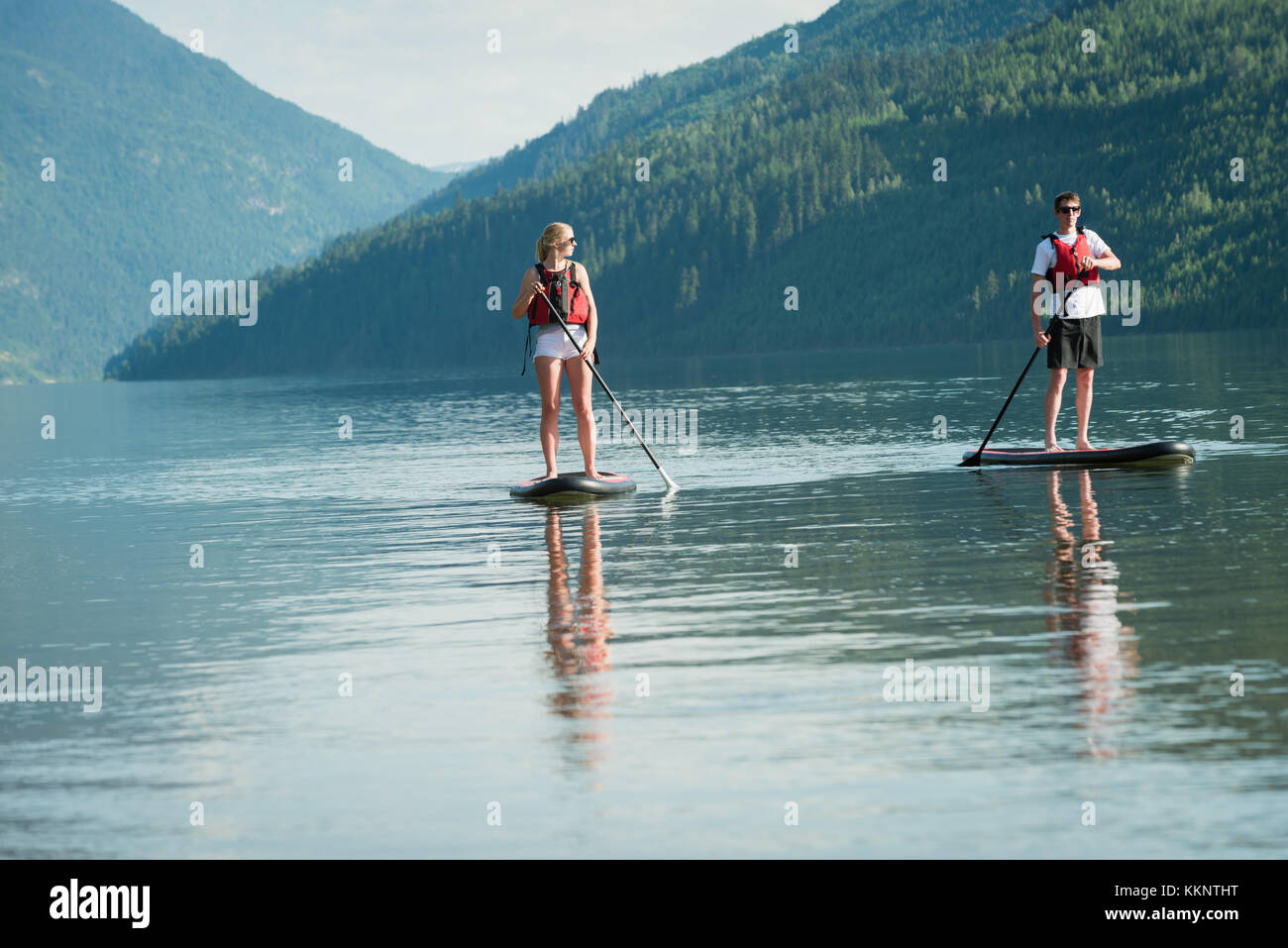 Couple doing stand up paddleboarding in river Stock Photo - Alamy