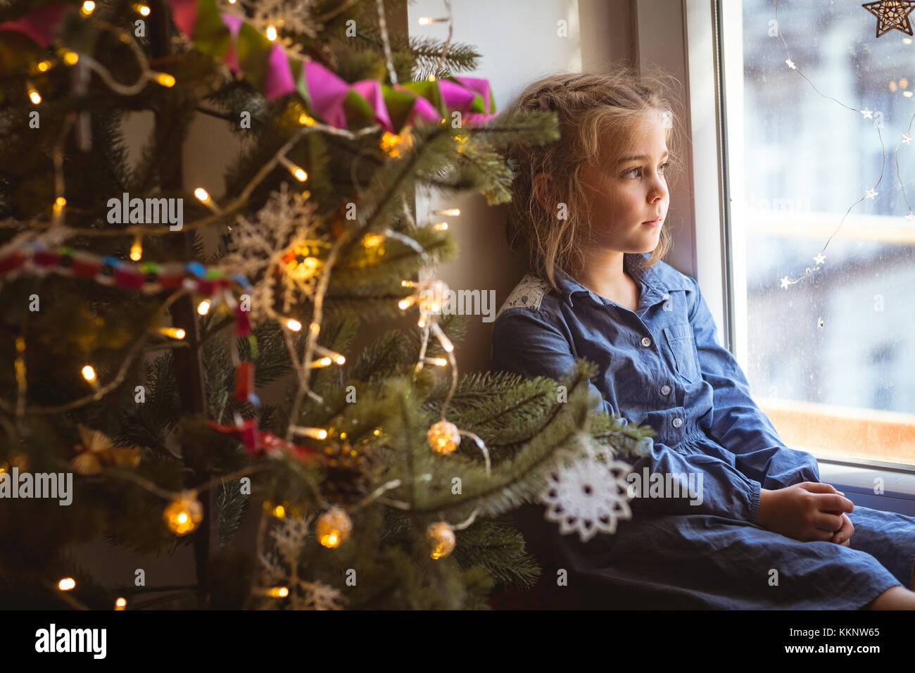 Girl looking through window during christmas Stock Photo - Alamy