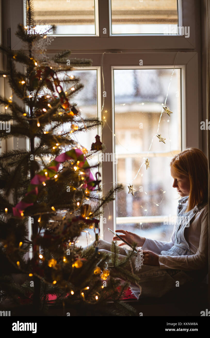 Girl sitting near window and using digital tablet at home Stock Photo ...