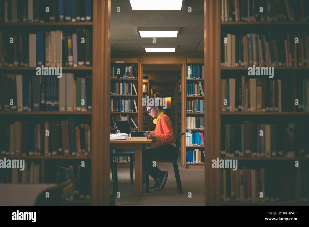 Girl reading book in library Stock Photo - Alamy