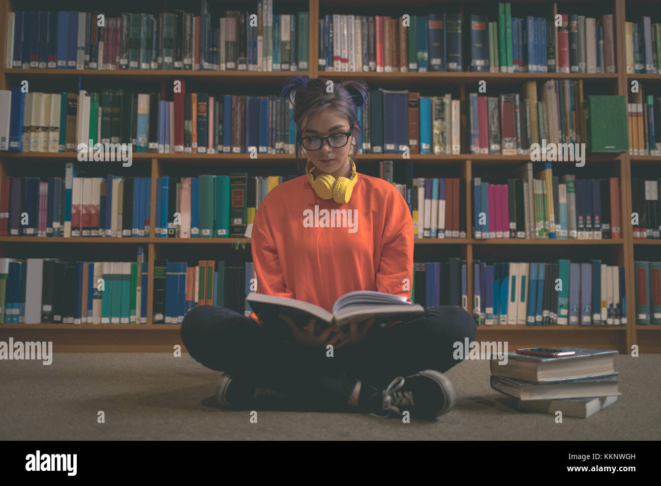 Girl reading book in library Stock Photo - Alamy
