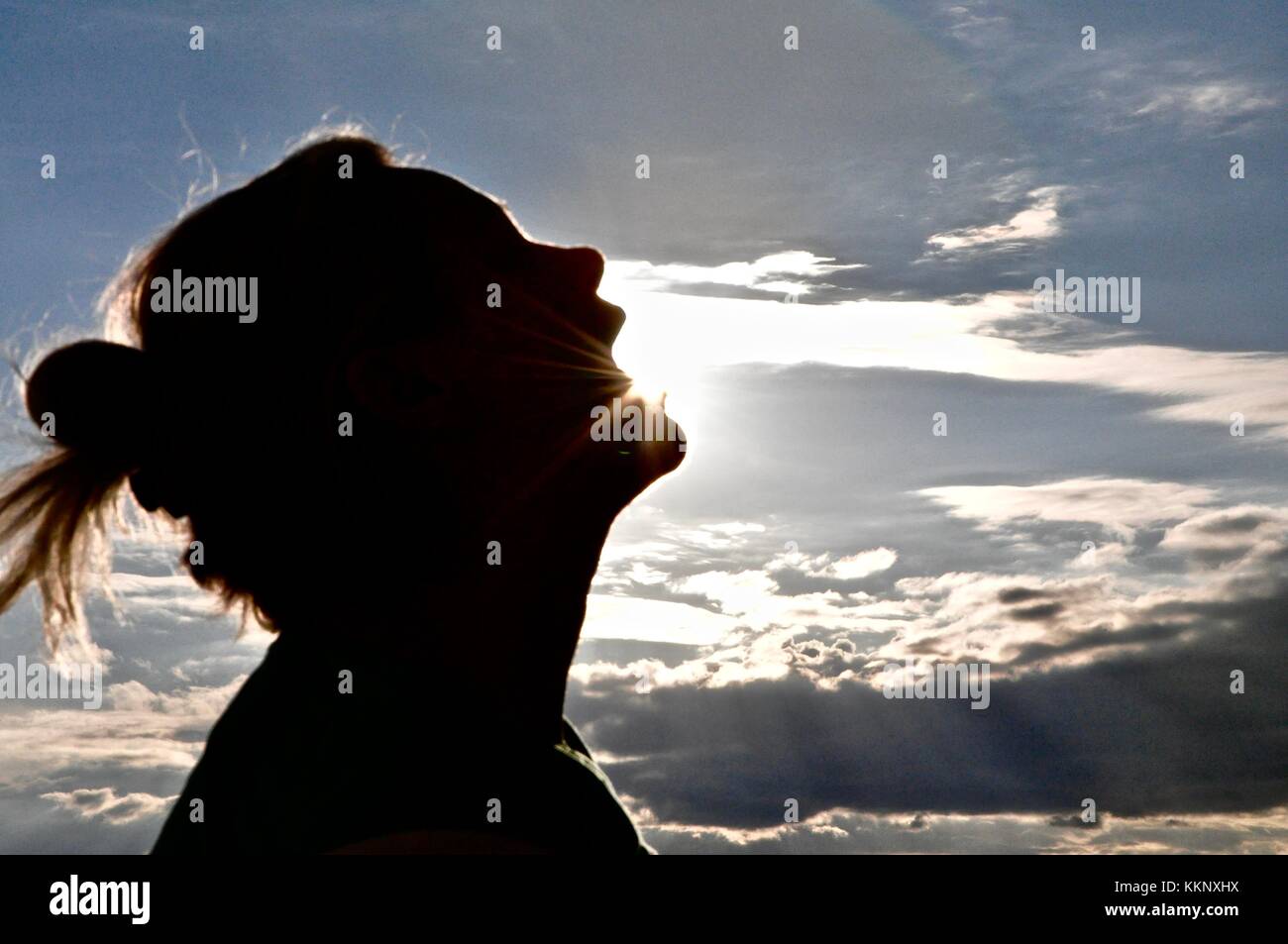 Silhouette of beautiful woman with open mouth eating sun.Girl is ...