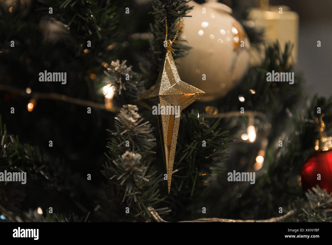 Christmas gold star hanging on a beautiful Christmas tree surrounded by ...