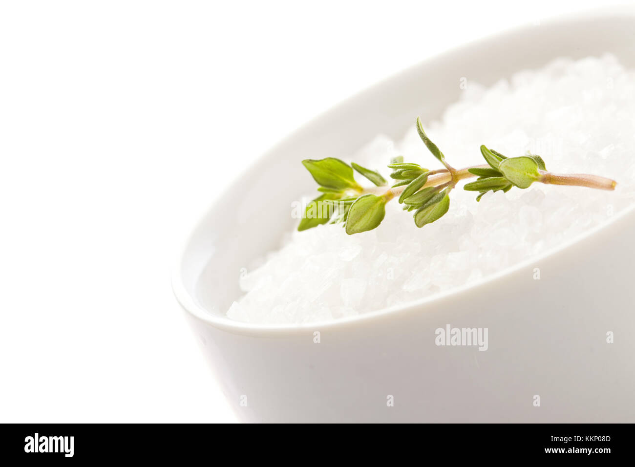 photo of white raw sea salt with parsley on white isolated background ...