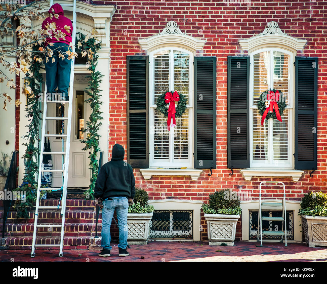 Workers hanging Christmas wreaths on a colonial home in northern ...