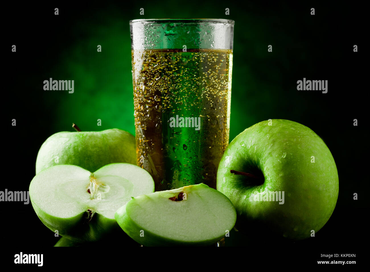 Fresh sparkling green apple juice on green spot lighted background ...