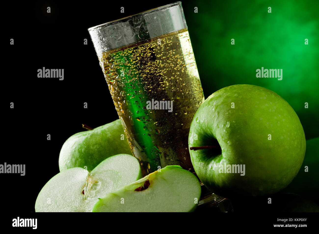 Fresh sparkling green apple juice on green spot lighted background ...