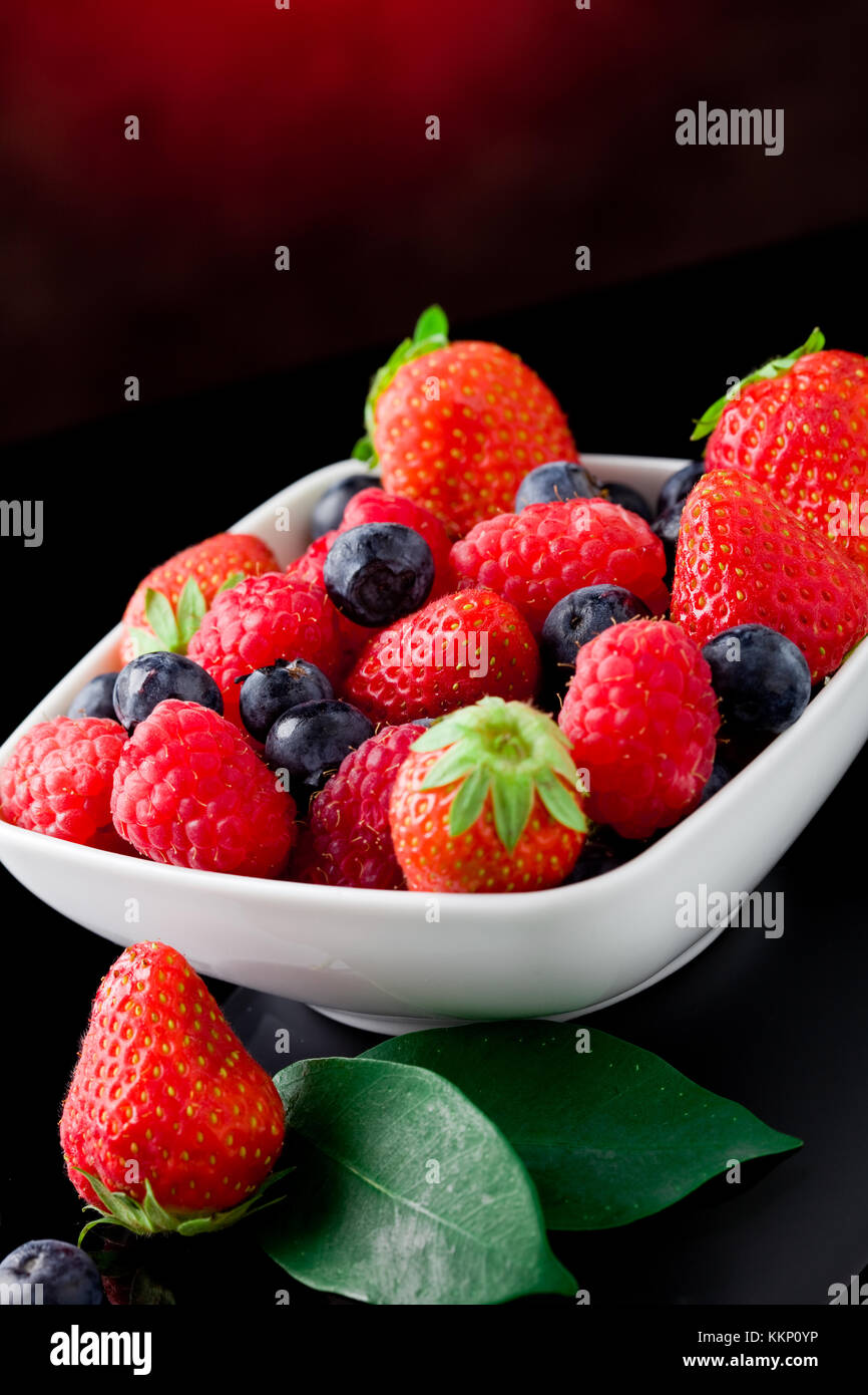 photo of mixed fresh berries on red lighted background Stock Photo - Alamy