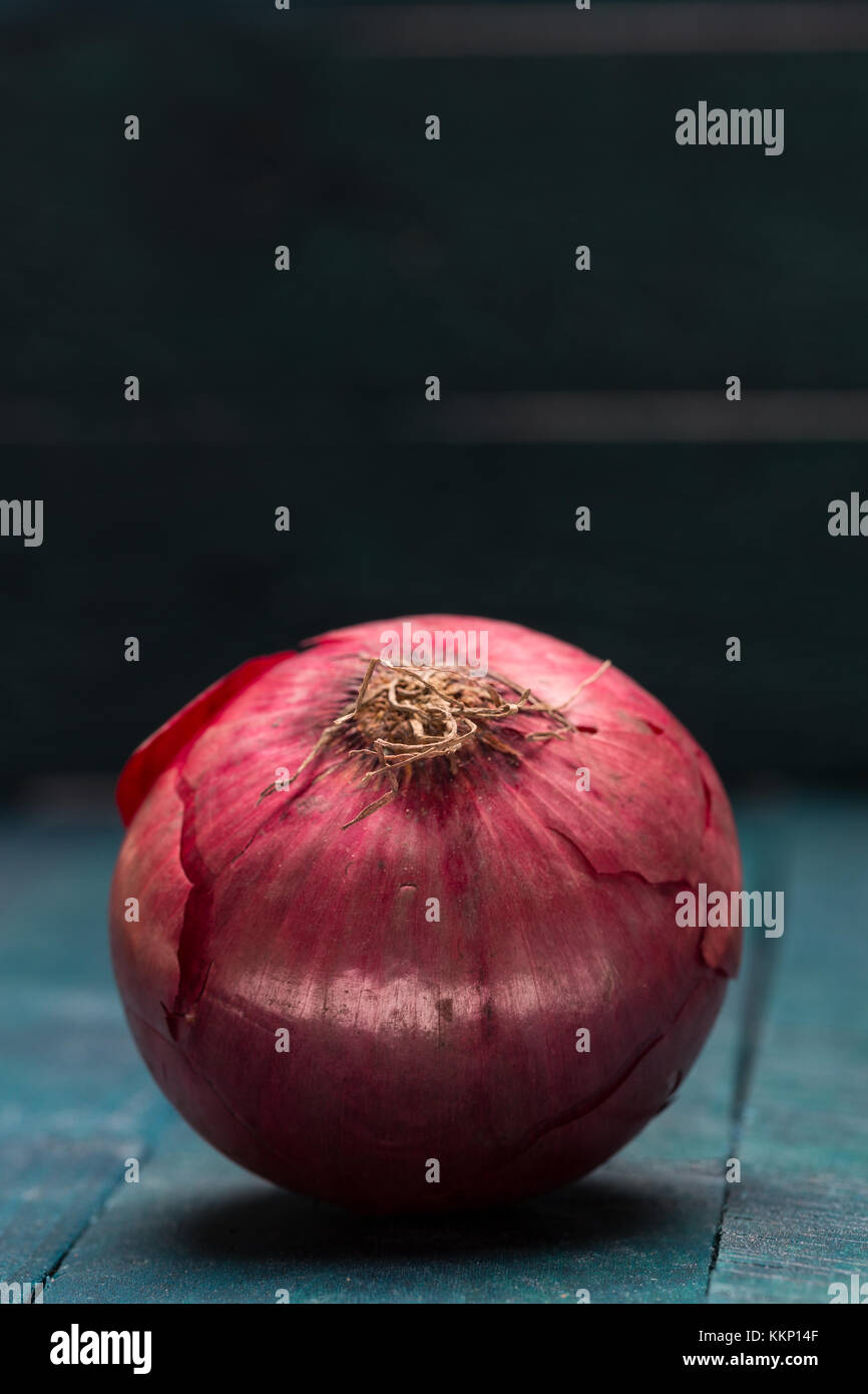 Red onion on petrol-colored wooden background Stock Photo - Alamy