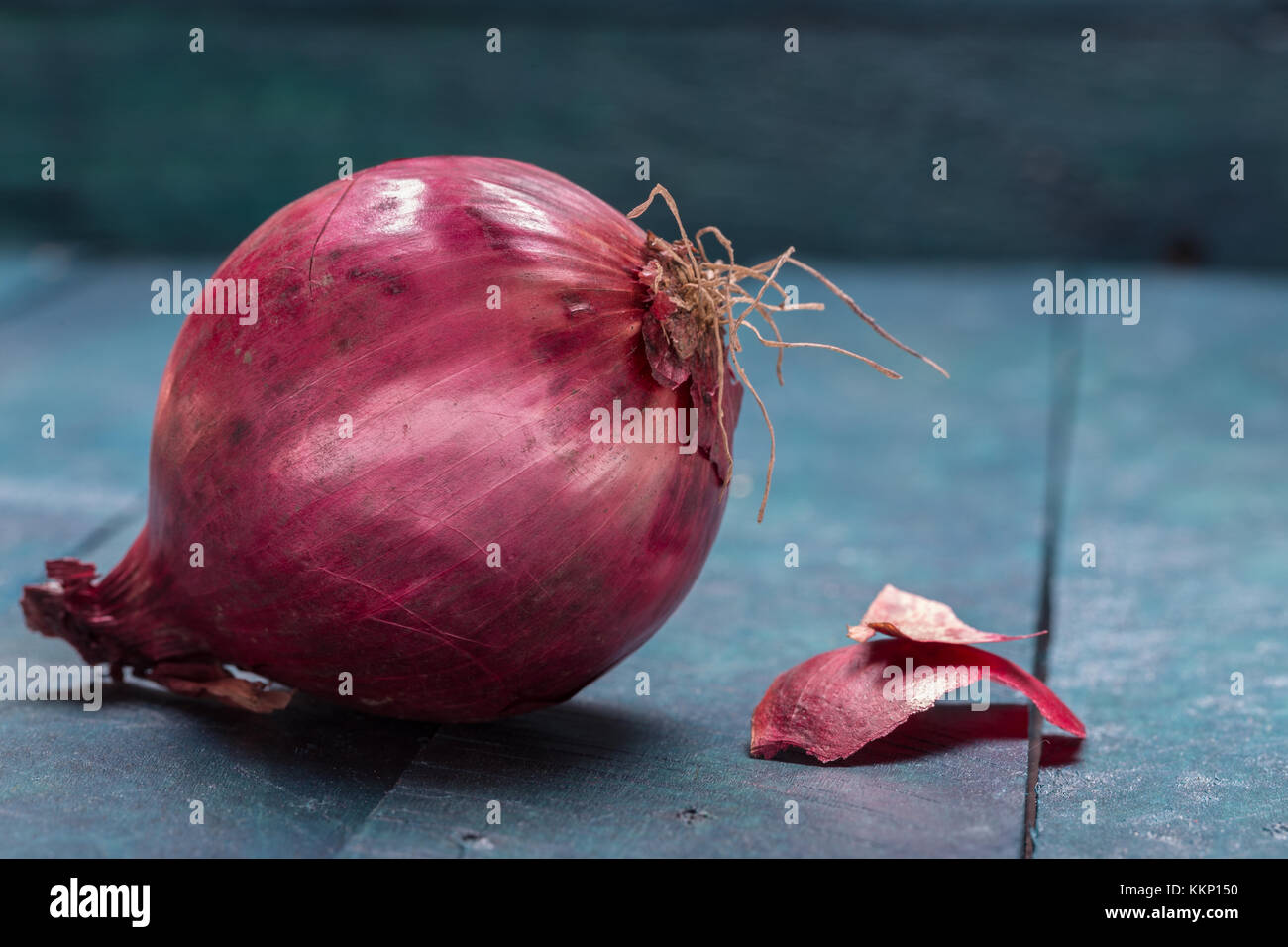 Red onion on petrol-colored wooden background Stock Photo - Alamy