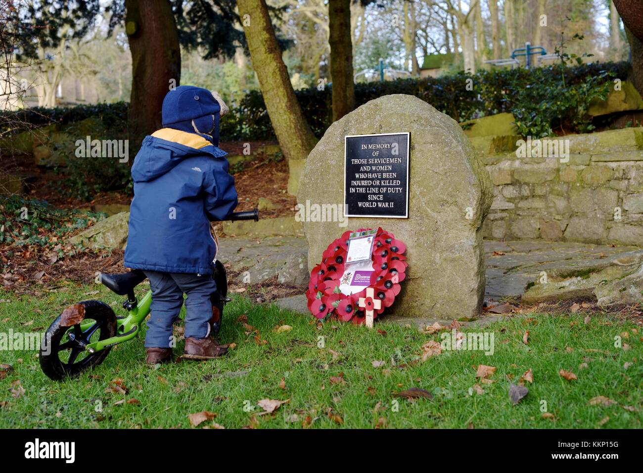 A young boy looks a wreath placed on a war memorial stone in High Lea ...