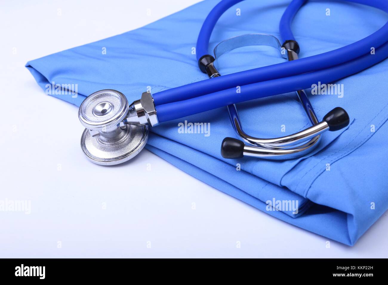 Medical stethoscope head lying on blue doctor uniform closeup. Medical ...