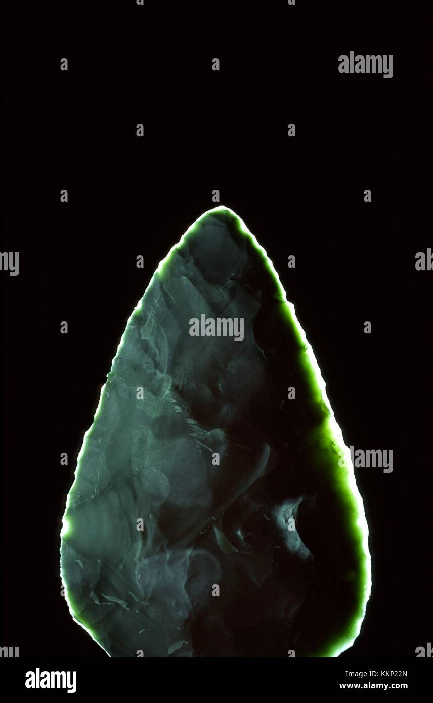 Flint stone spear axe head. Back lit showing sharp knapped translucent ...