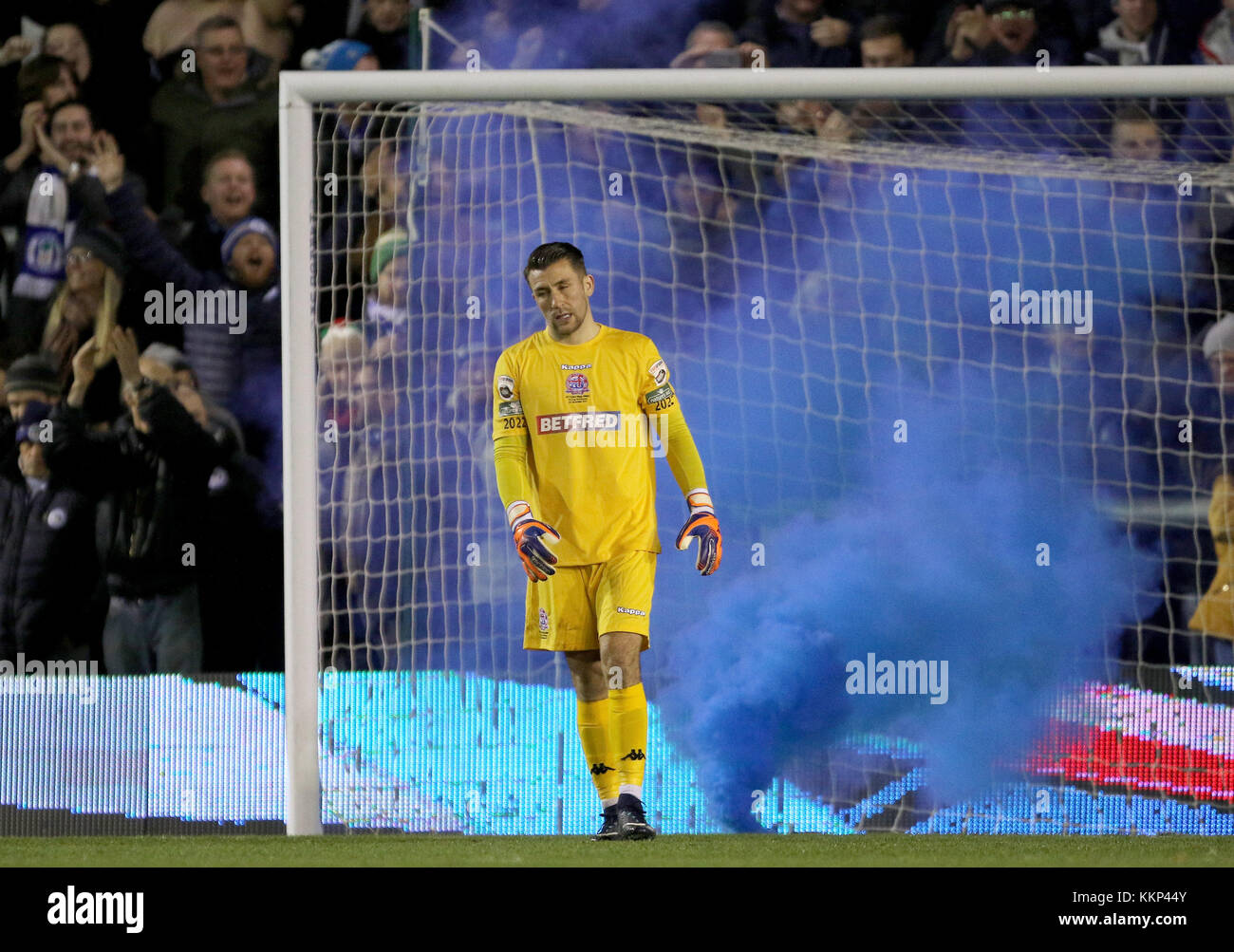 Fylde's Rhys Taylor looks dejected after Wigan score and a flare is set ...