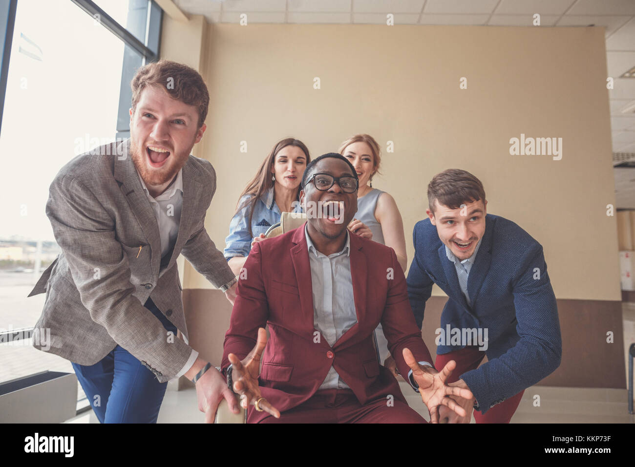 Positive colleagues having fun with office chairs Stock Photo - Alamy