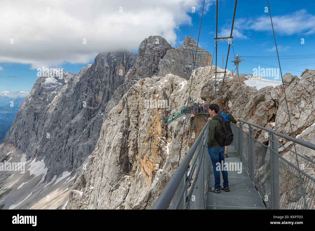 Austrian Dachstein Mountains with hikers passing a steel rope bridge ...