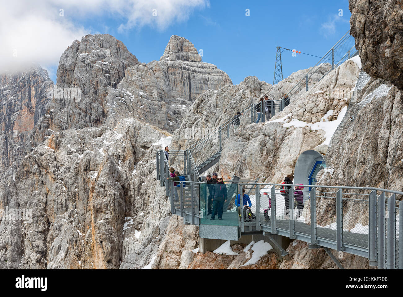 Austrian Dachstein Mountains with hikers passing a skywalk rope bridge ...