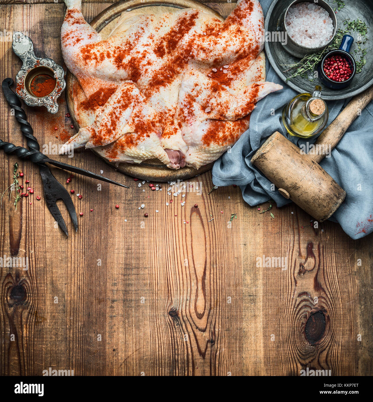 Whole chicken flattened out with condiment and kitchen tools on wooden ...