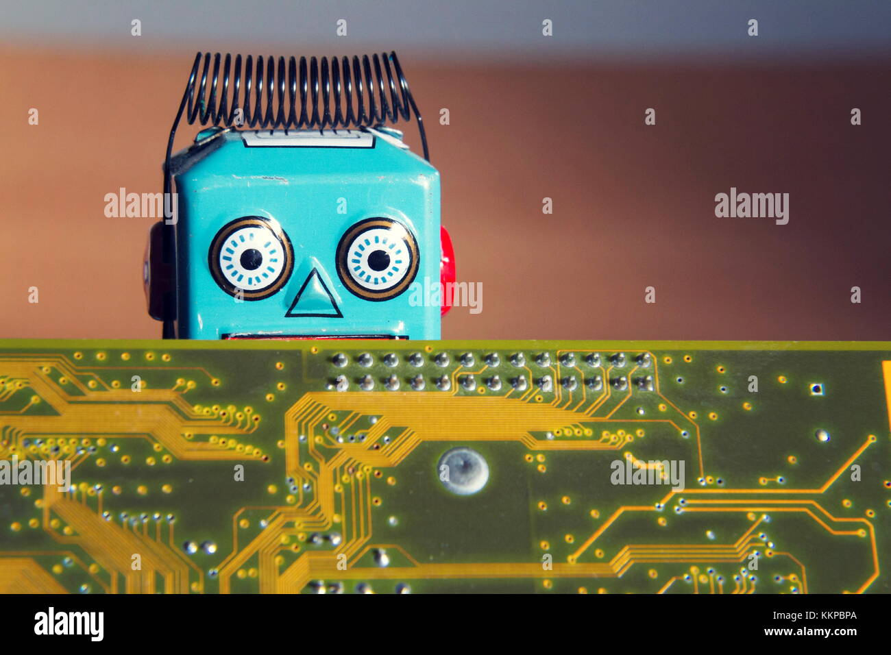 Vintage tin toy robot behind computer board, artificial intelligence ...