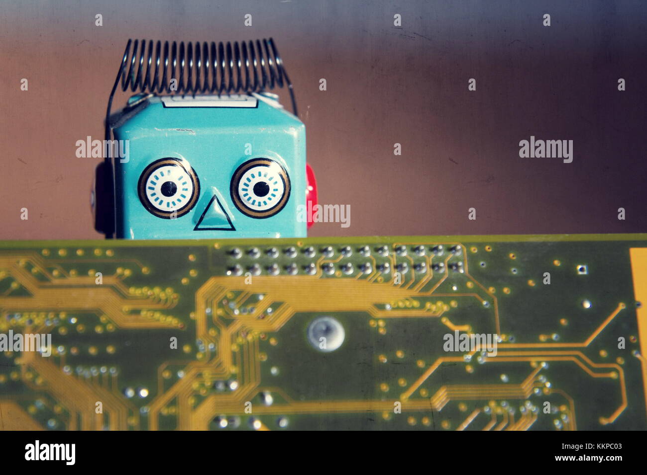 Vintage tin toy robot behind computer board, artificial intelligence ...
