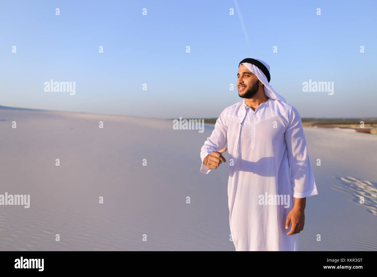 Stately young sheikh walks on foot along bottomless desert leaving ...