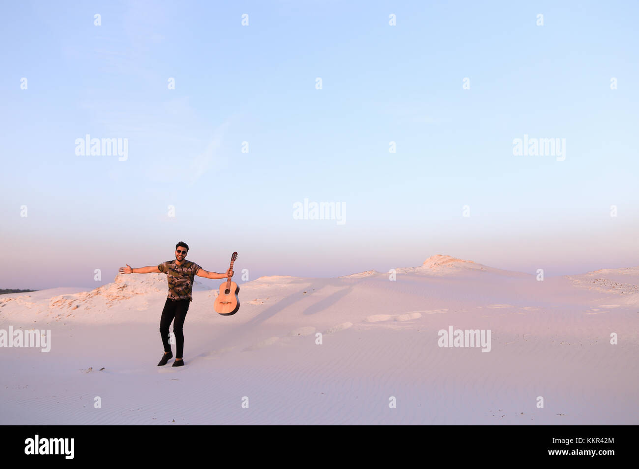 Young Muslim male performer and singer walks through sandy desert with ...