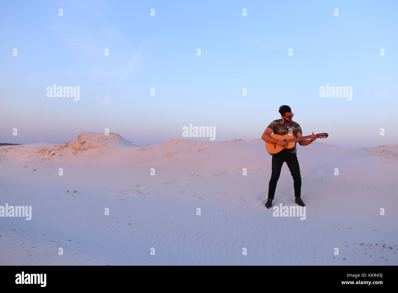Young Muslim male performer and singer walks through sandy desert with ...