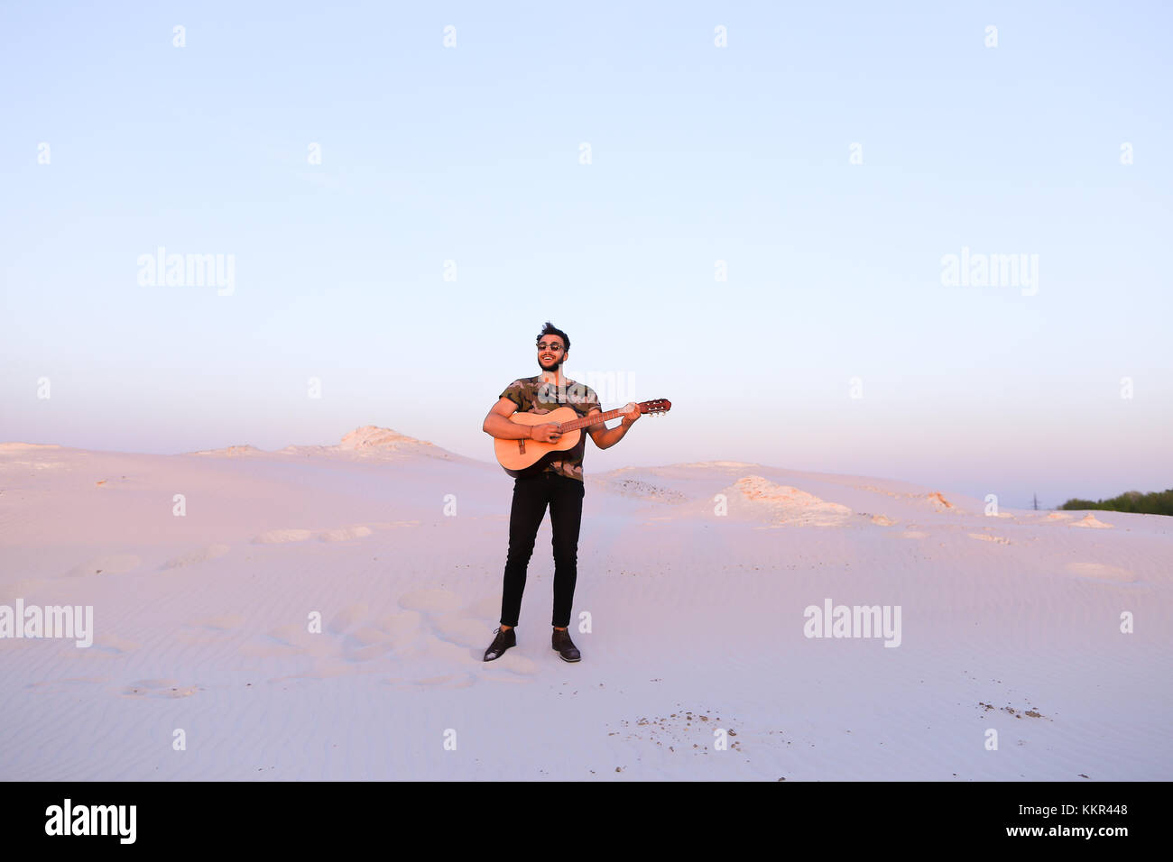 Young Muslim man stands at full length and plays melody on stringed ...