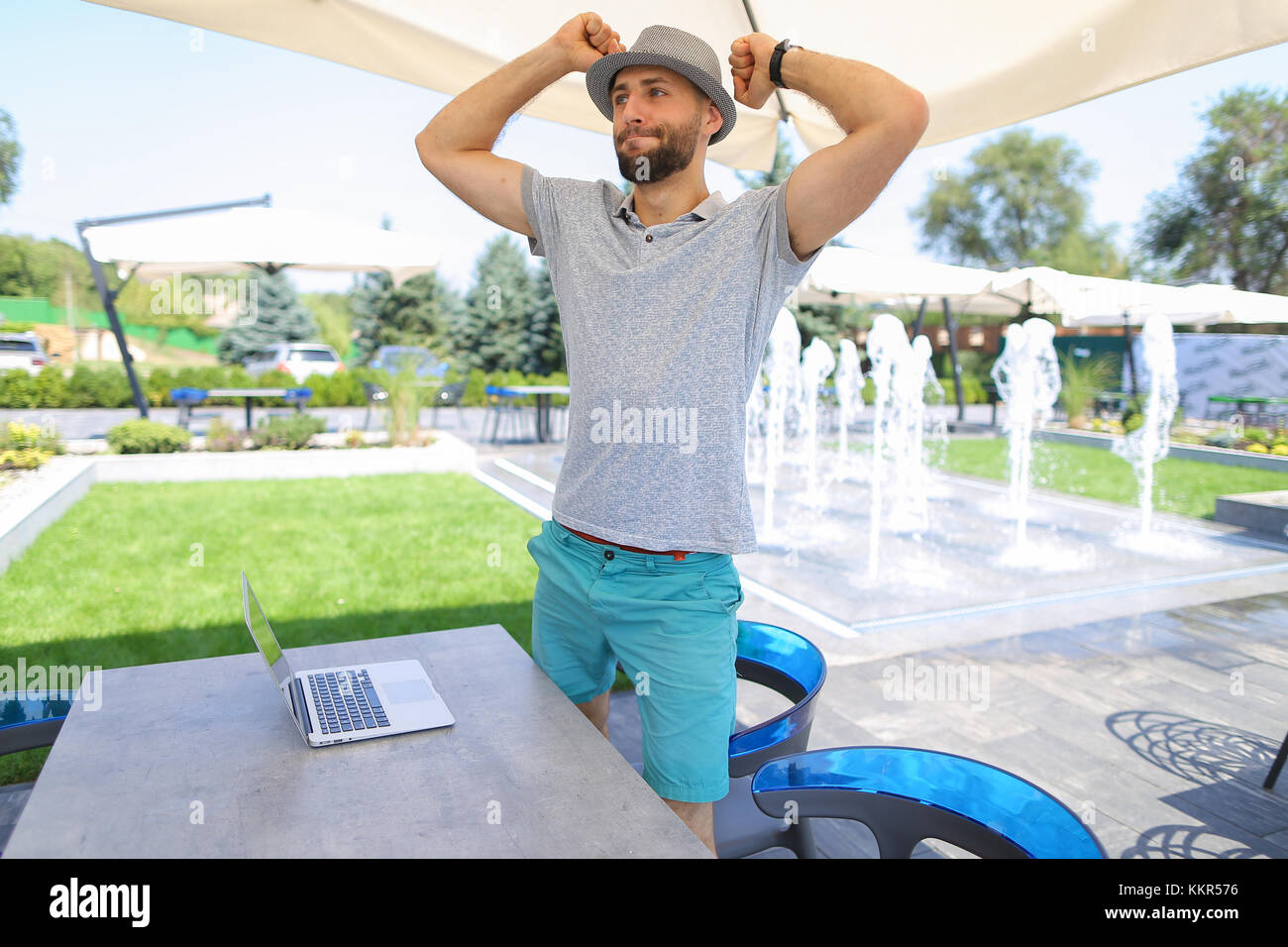 Happy man rejoicing successful bet with laptop outside near fountain ...