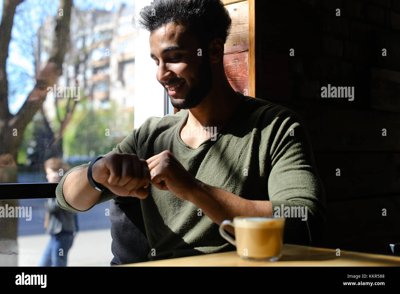 Arab guy sits in caf and texting e-mail by smart watch. Happy boy has ...