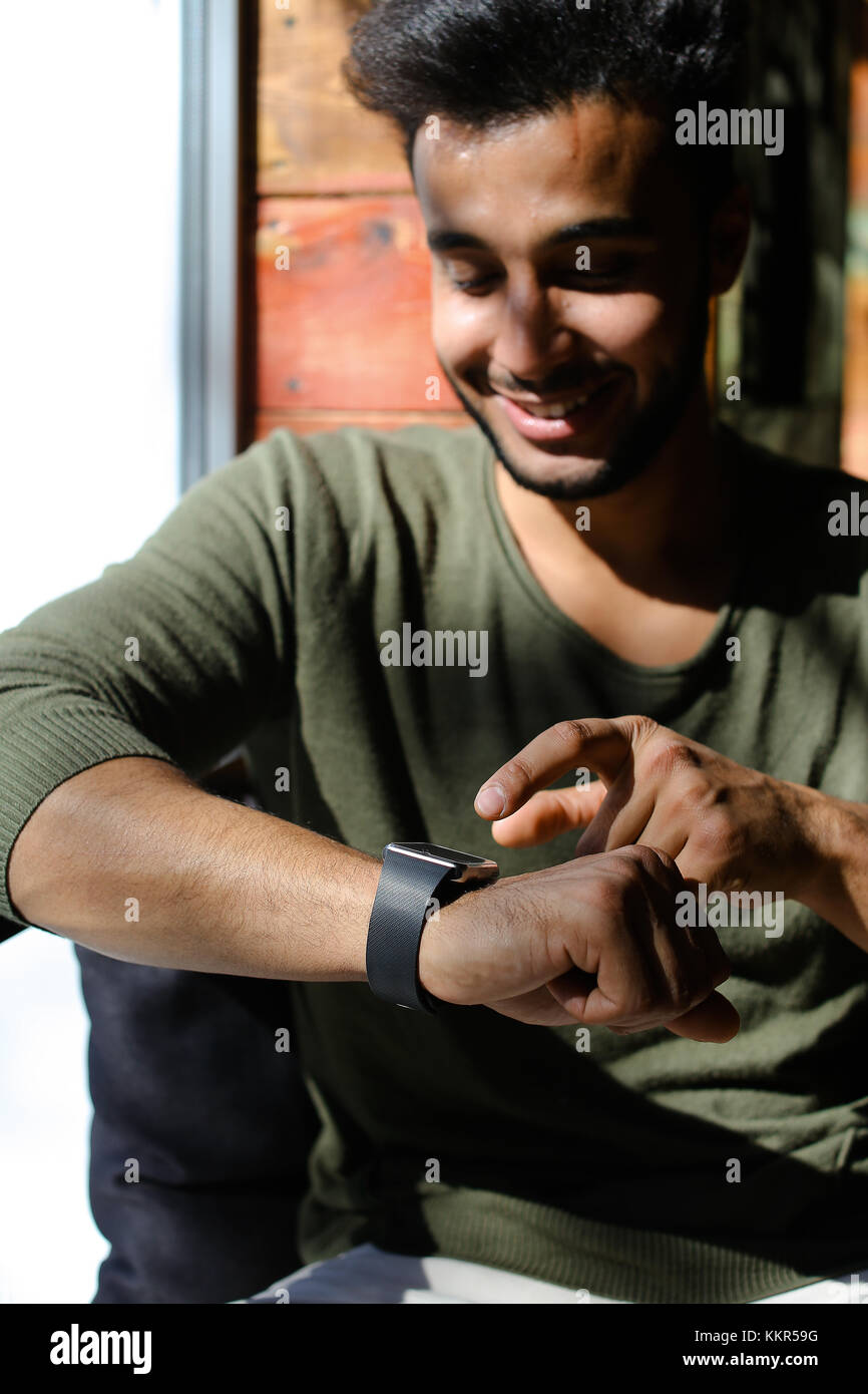 Arabian sits near window and uses smart watch in caf . Person dressed ...