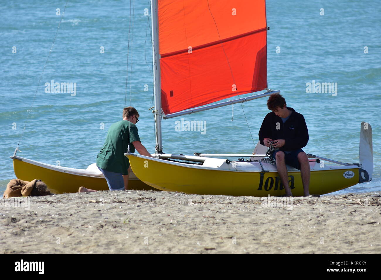 Small sailing catamaran with colorful sail being prepared for launch by ...