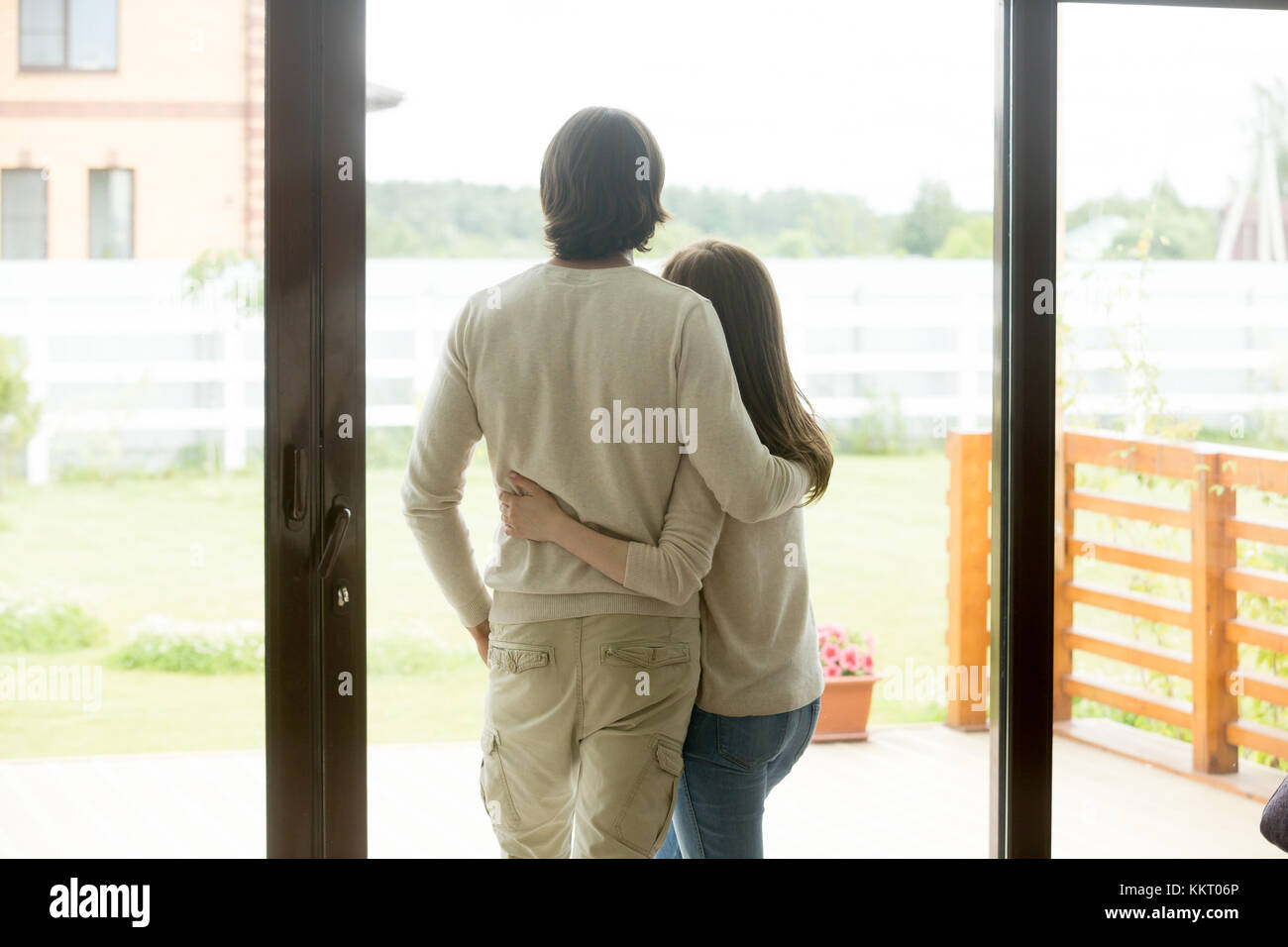 Couple standing at home, embracing looking outside, rear view Stock ...