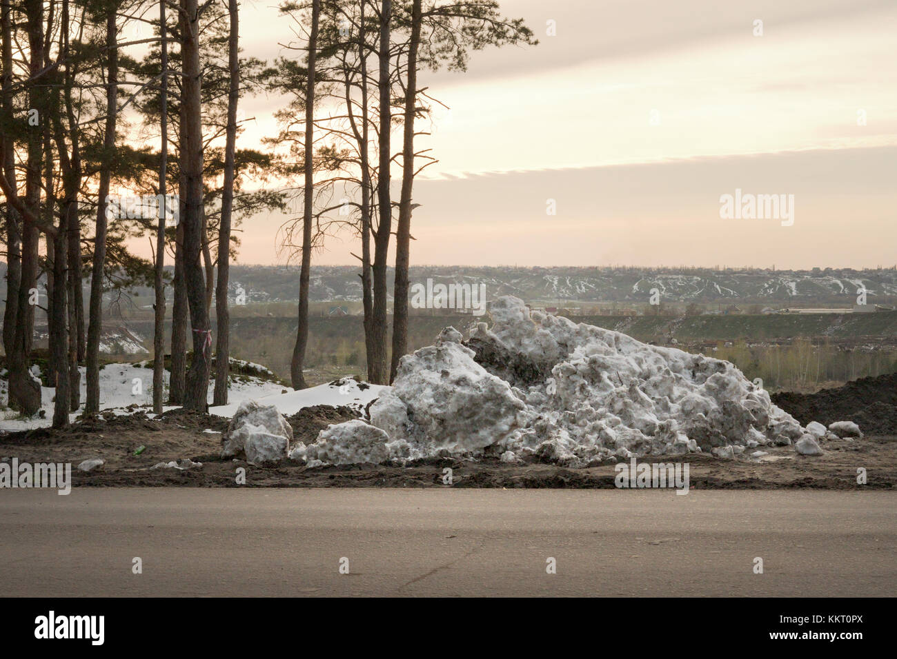 big pile of snow near the road, left after the winter. cliff edge and ...