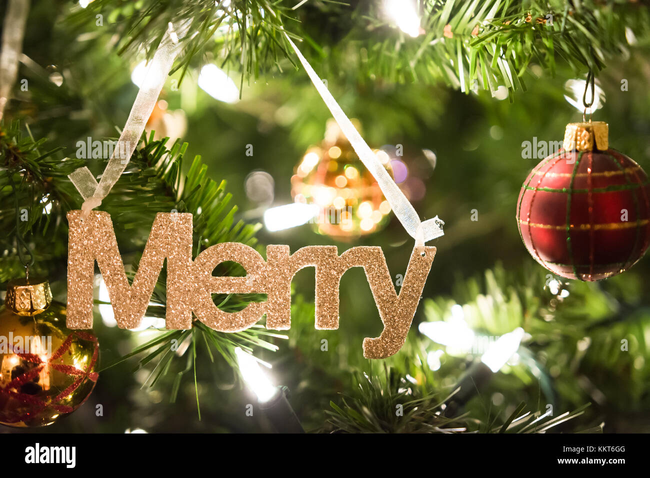 Glittery Merry word hanging on Christmas Tree branch Stock Photo - Alamy