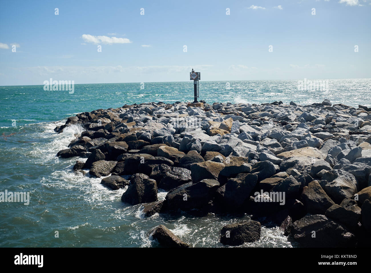 Sea wall or breakwater built of natural rocks with a beacon at the end ...