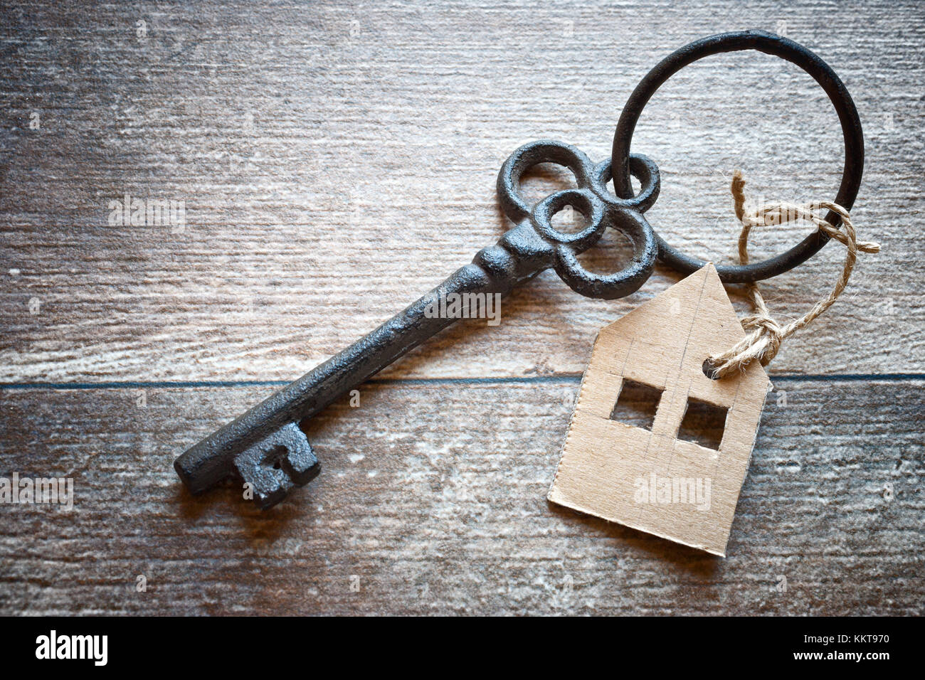 old metal key with symbol of a family house on the wooden background ...