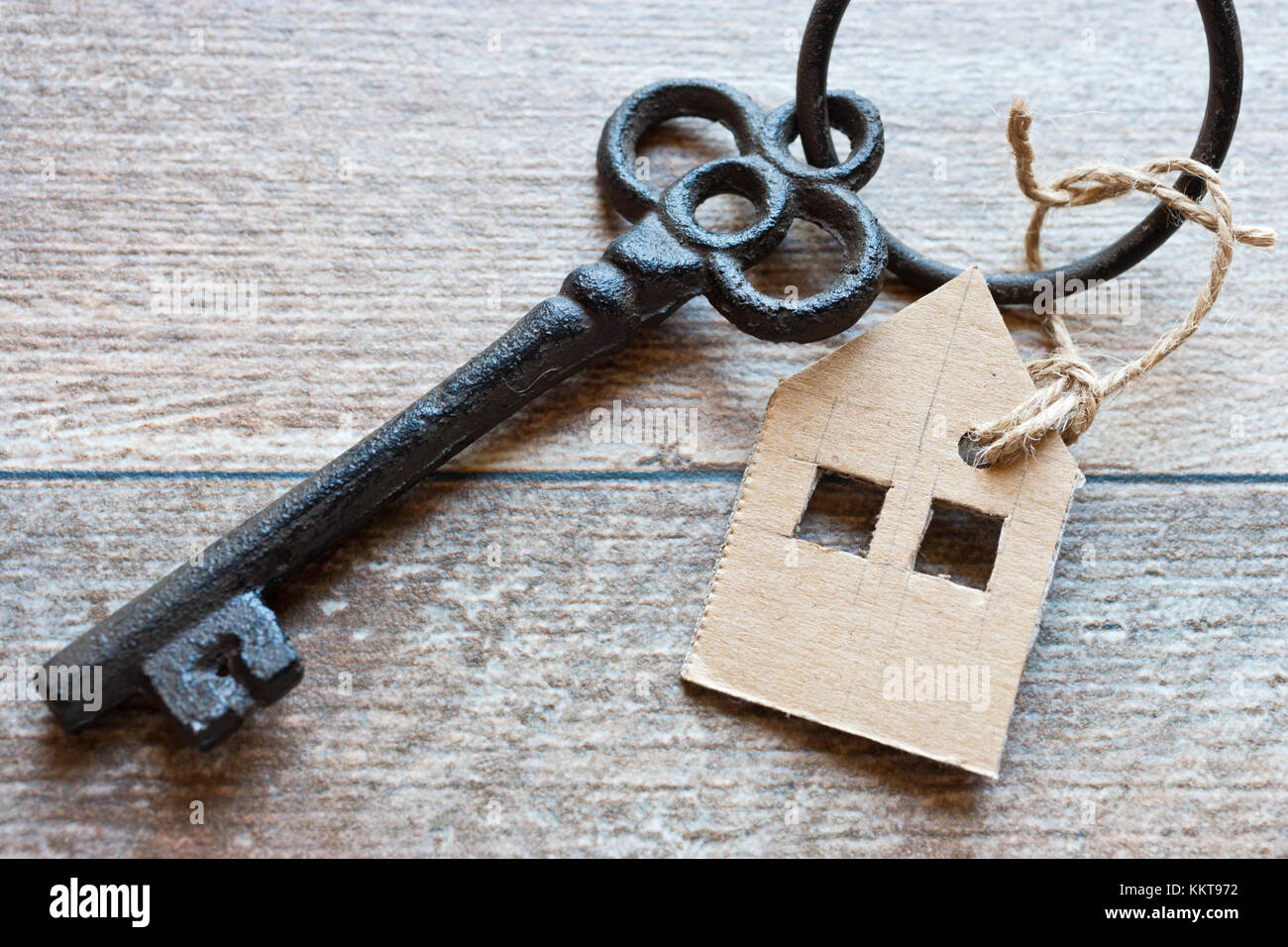old metal key with symbol of a family house on the wooden background ...