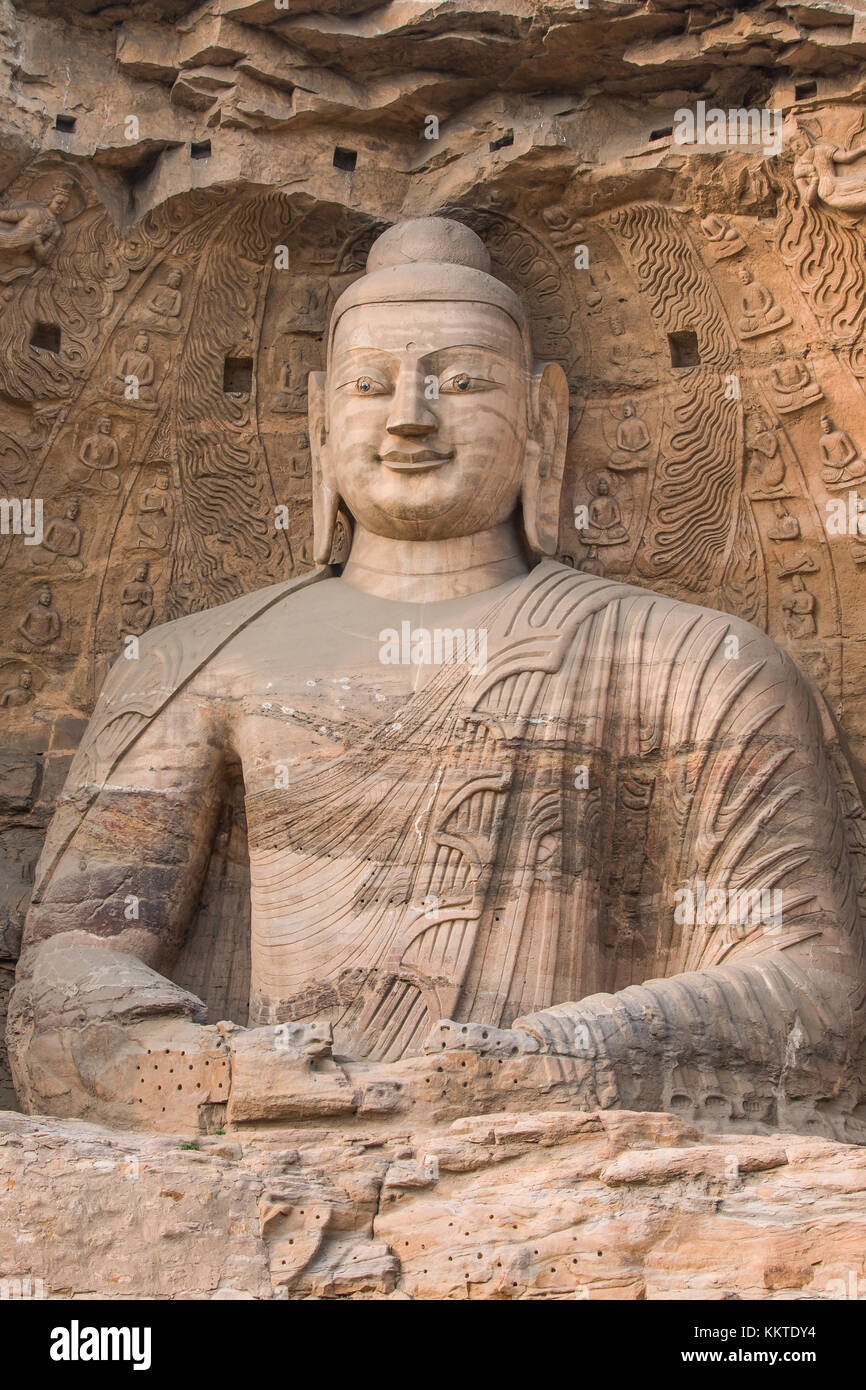 Giant Buddha carved from a reddish brown stone, housed in a cave at the ...
