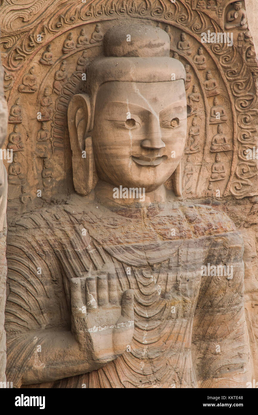 Giant Buddha carved from a reddish brown stone, housed in a cave at the ...