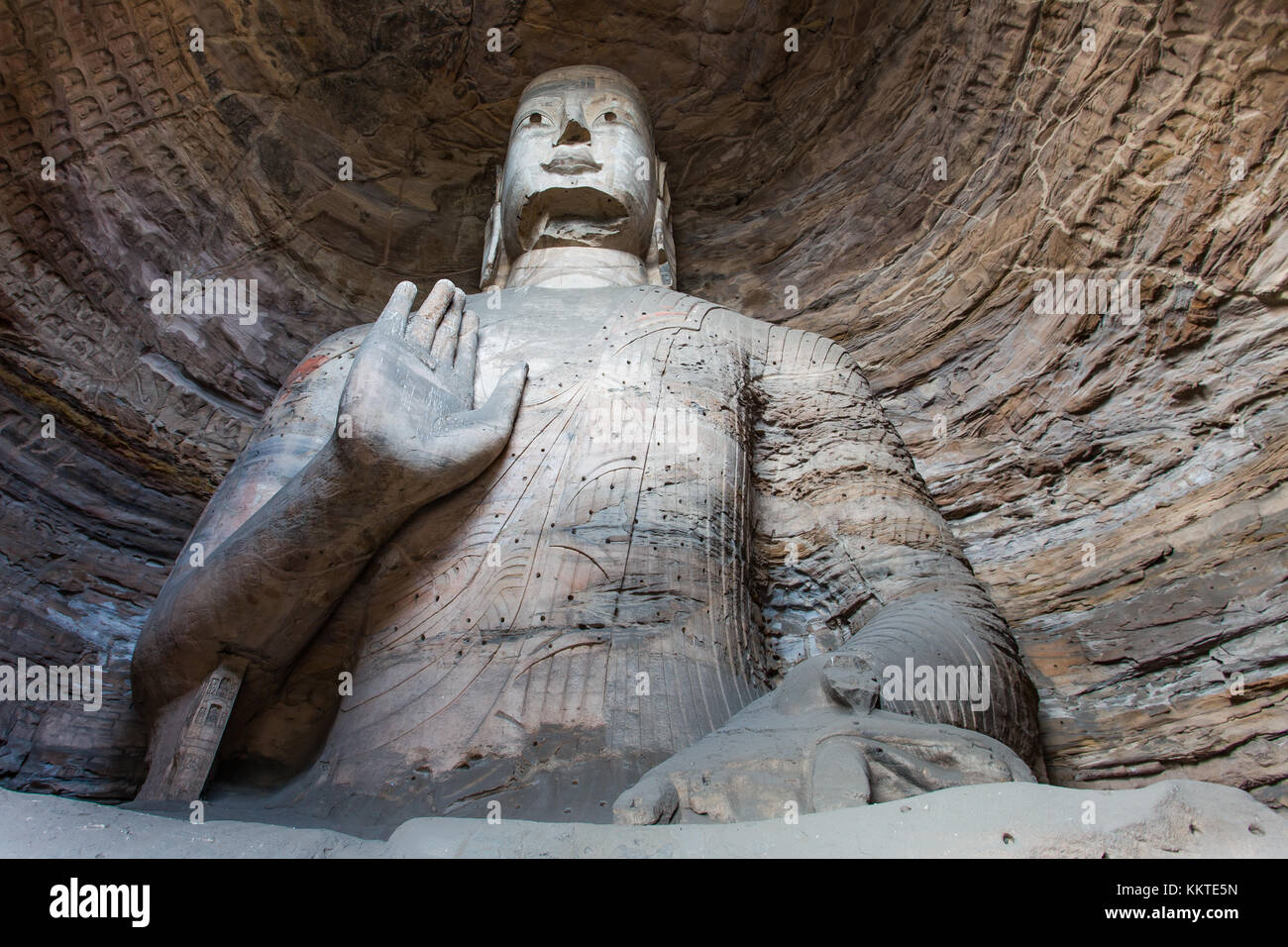Giant Buddha carved from stone, housed in a cave at the Yungang Grottos ...