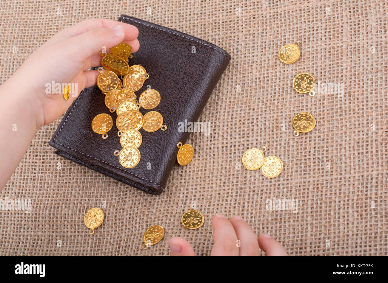 Wallet and plenty of fake gold coins in hnad Stock Photo - Alamy
