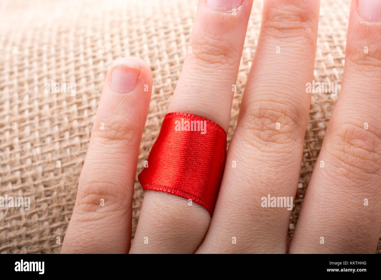 Red string tied around ring finger of the hand Stock Photo - Alamy