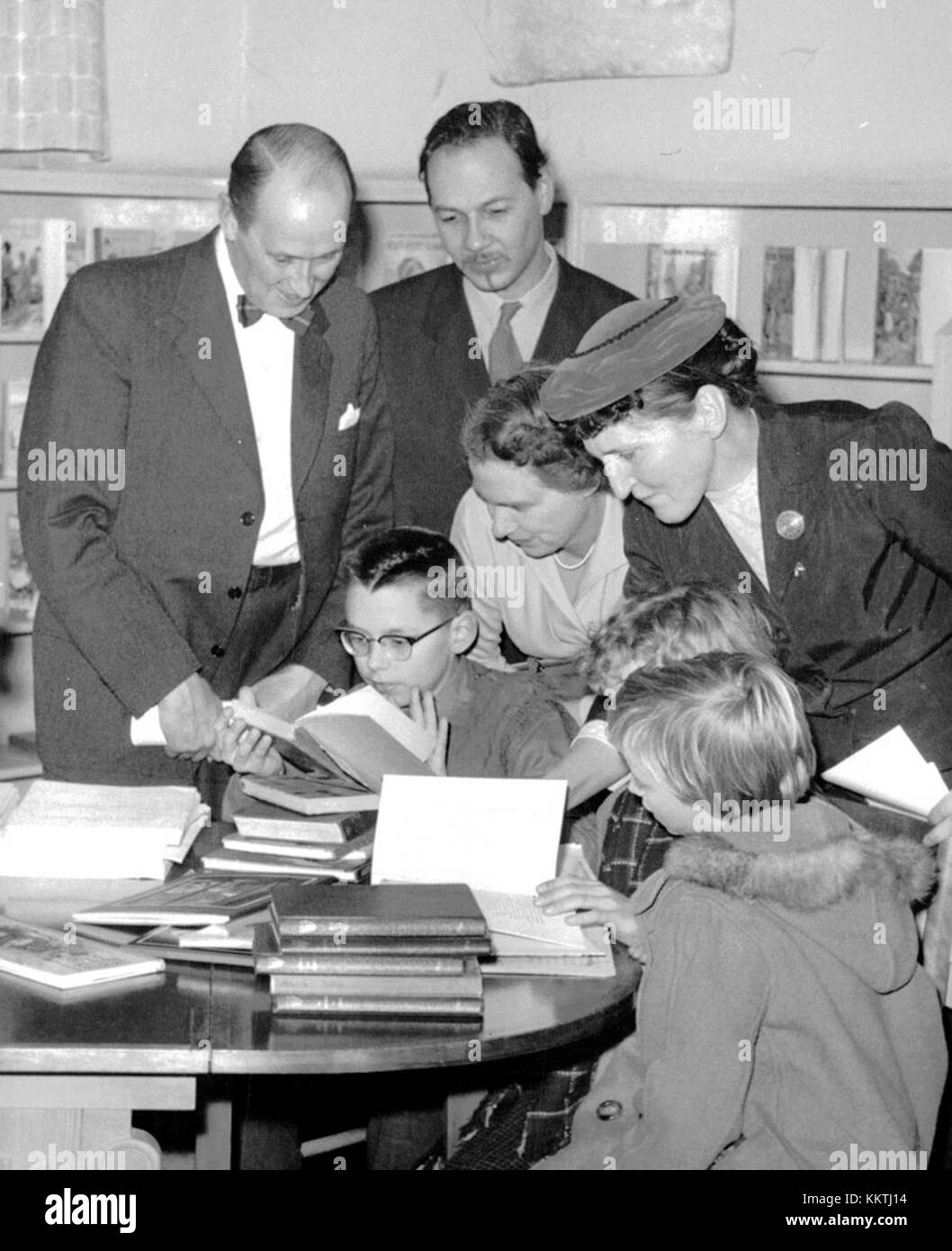 An author is seen reading children's books to a group of students. The ...