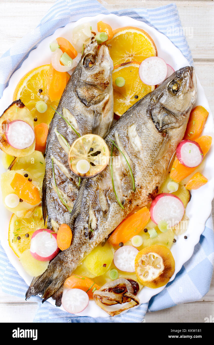 Prepared bass fish in the plate ith vegetables and fruit Stock Photo ...